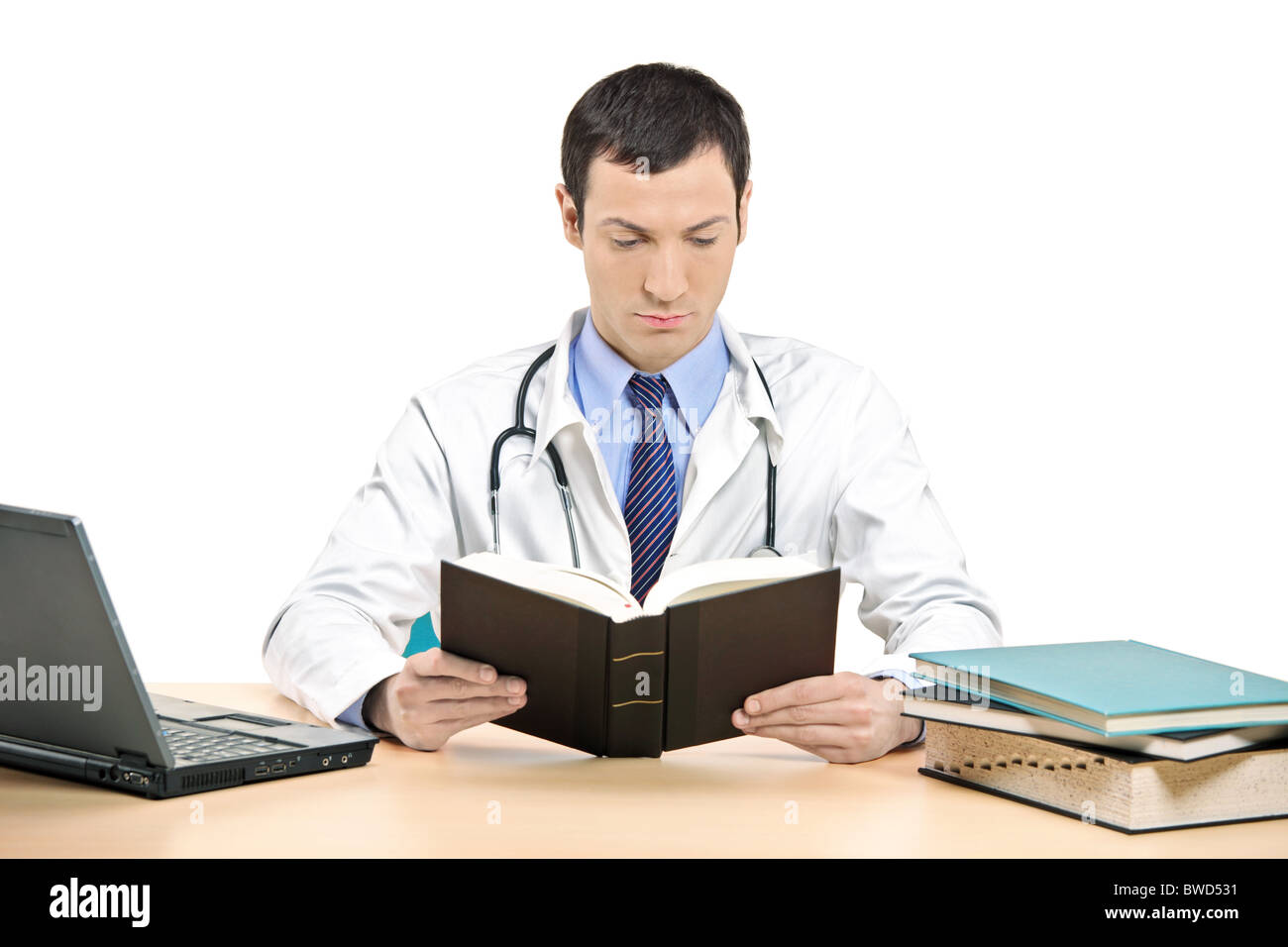 A male doctor reading a book in his office Stock Photo - Alamy