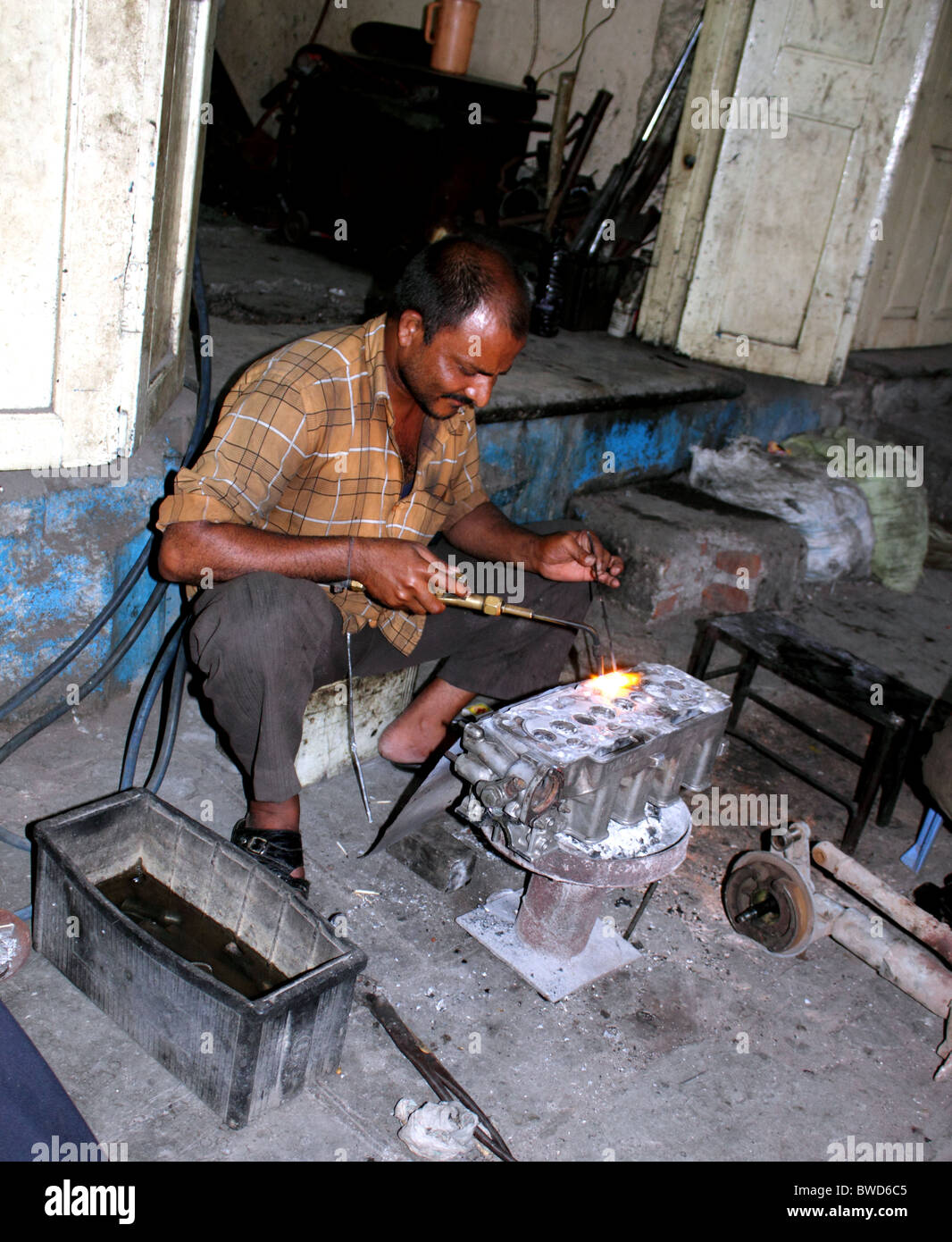 Indian man repairing car engine block by welding cylinder head using a ...