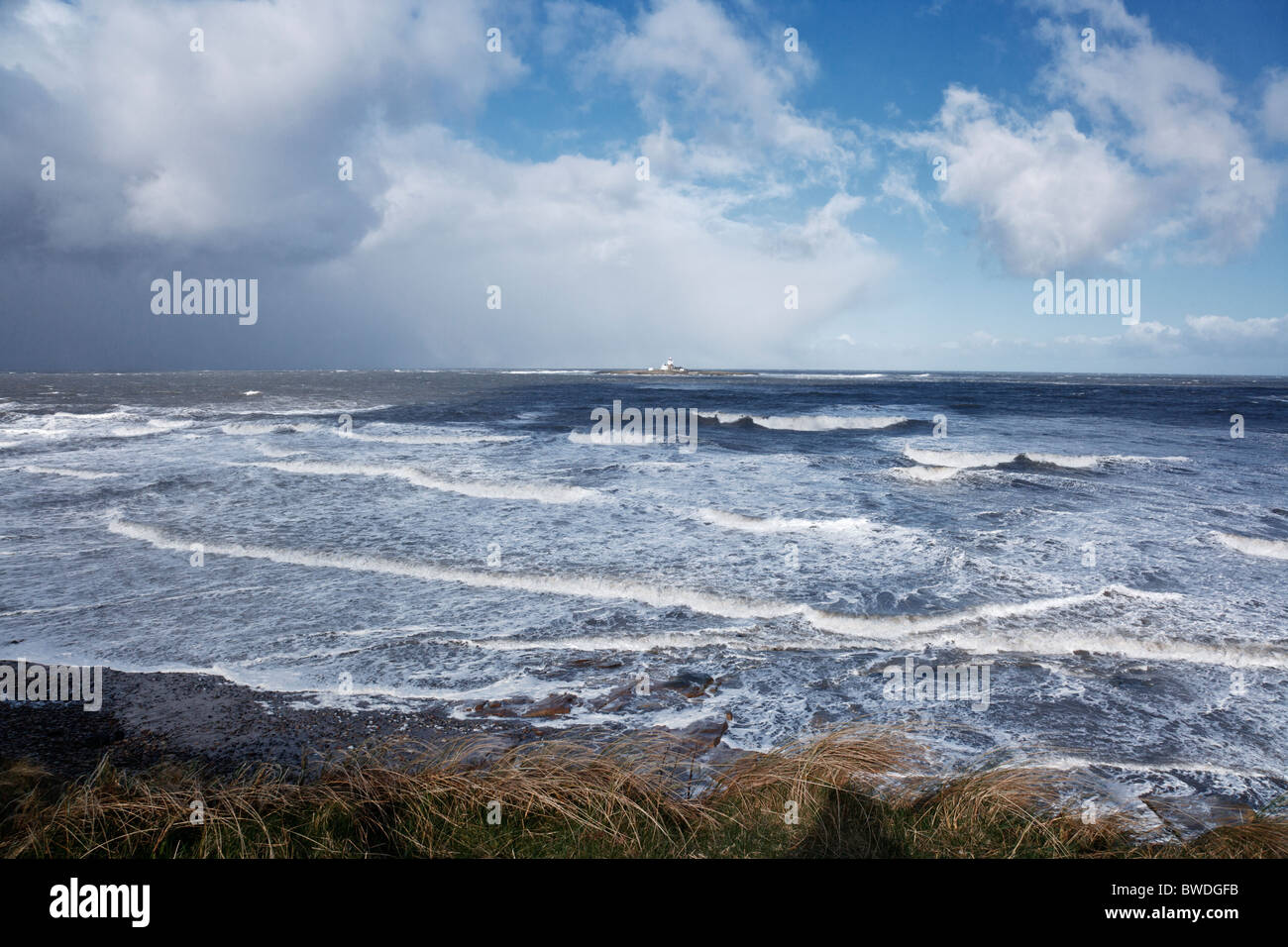 A distant view to Coquet Island Lighthouse in storm light and rough ...