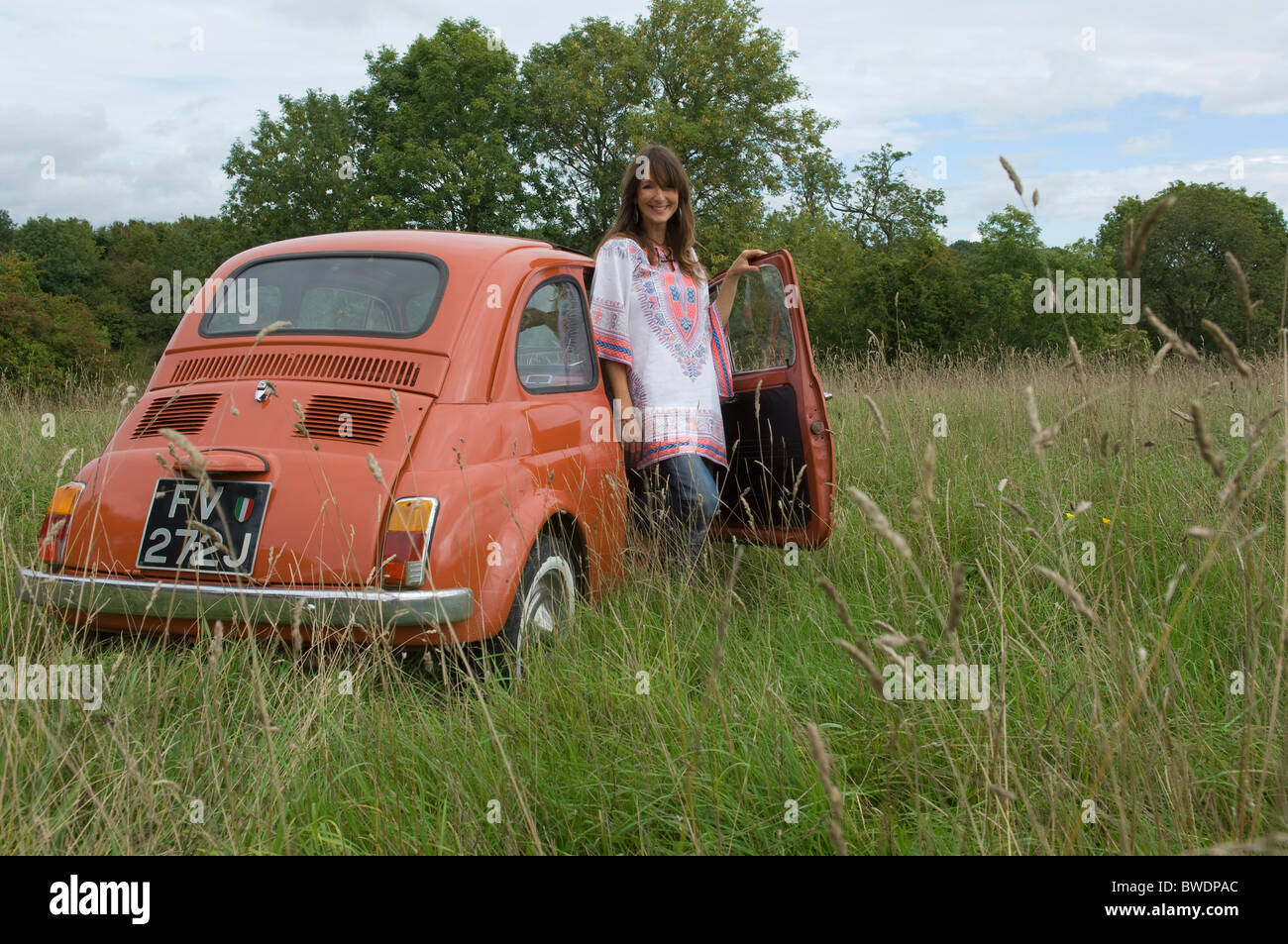 Smiling female with car in field Stock Photo - Alamy