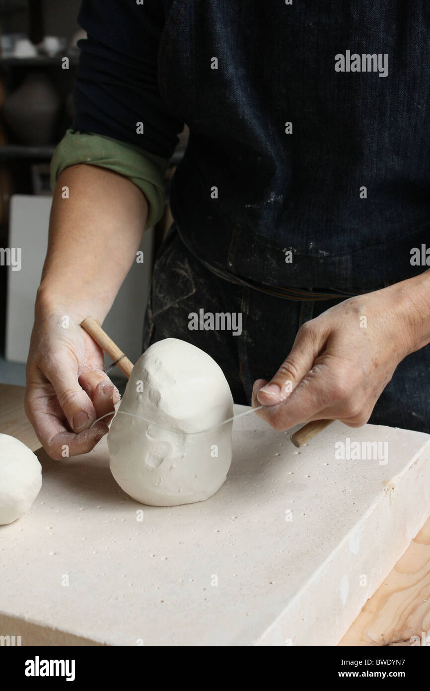 Close up of a female potter using a wire clay cutter for slicing ...