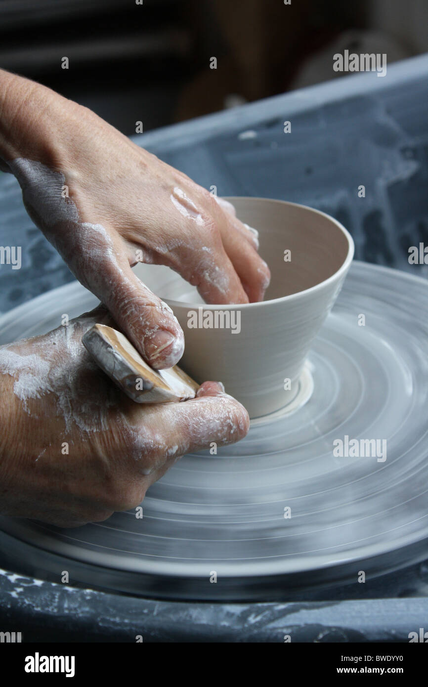 Hand of a female potter throwing a porcelain pot on a wheel and using a ...