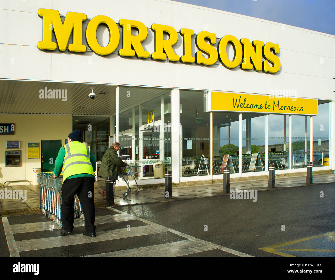 A Morrisons store employee pushing supermarket trollies Stock Photo - Alamy