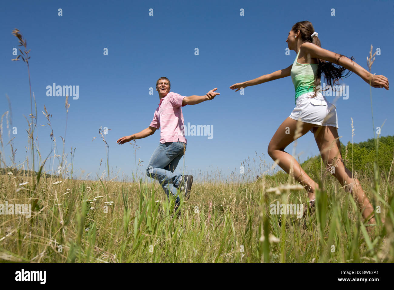 Attractive dates having fun while running down green field during ...