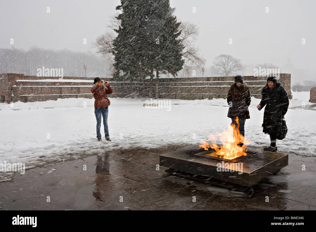 A woman photographing in a snowstorm two women by the eternal flame on ...