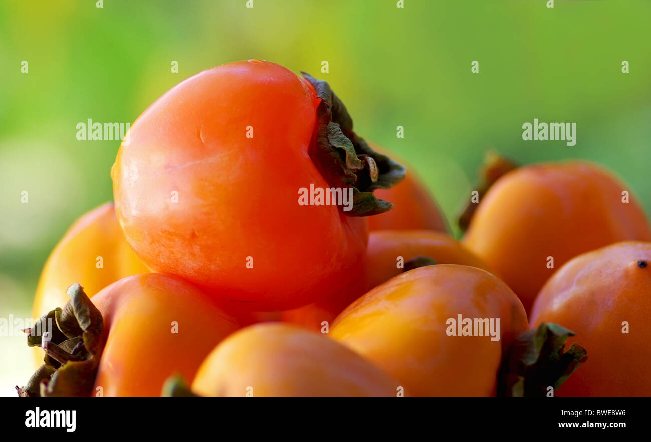Mature caqui fruits on green background Stock Photo - Alamy