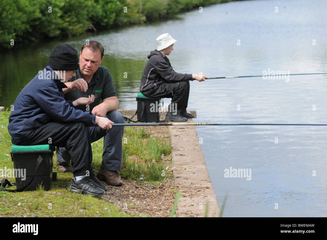 An angling instructor gives instructions to a young person learning to ...