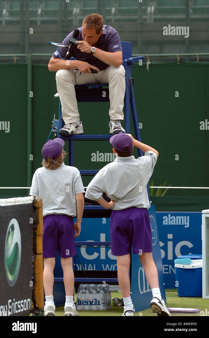 A tennis umpire sitting in a chair gives instructions to the ball boys ...