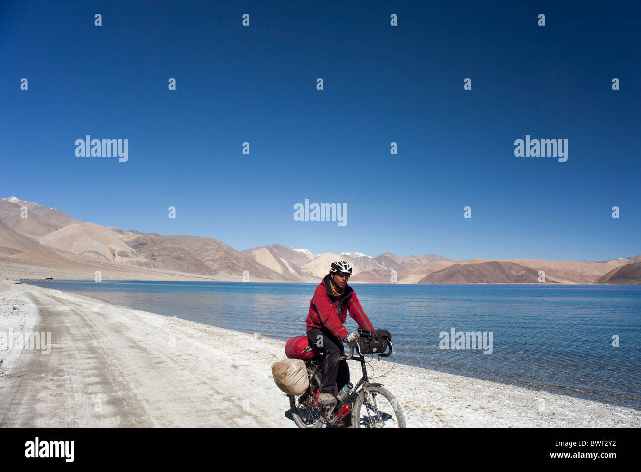 A lone cyclist riding his touring bike along the shores of the high ...
