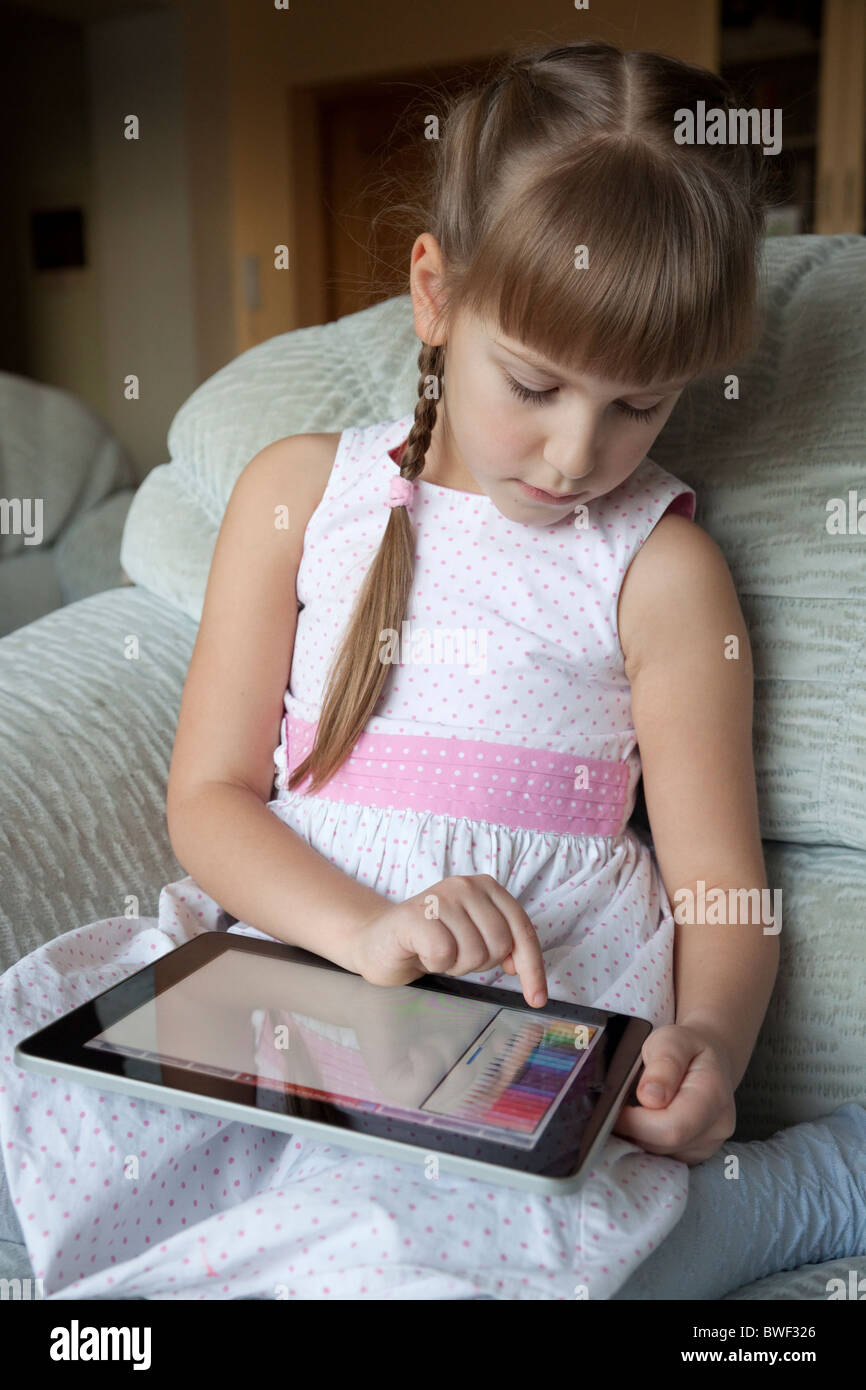 Little girl is using Apple iPad to draw and entertain herself at home ...