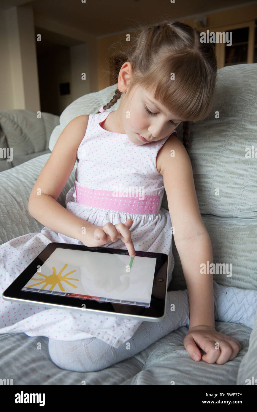 Little girl is using Apple iPad to draw and entertain herself at home ...