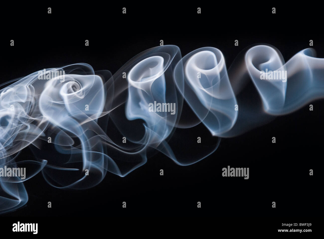 wavy smoke trail against black background creating patterns calmness ...