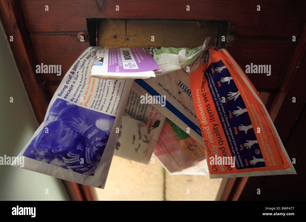 An assortment of charity collection bags stuffed through a letterbox ...