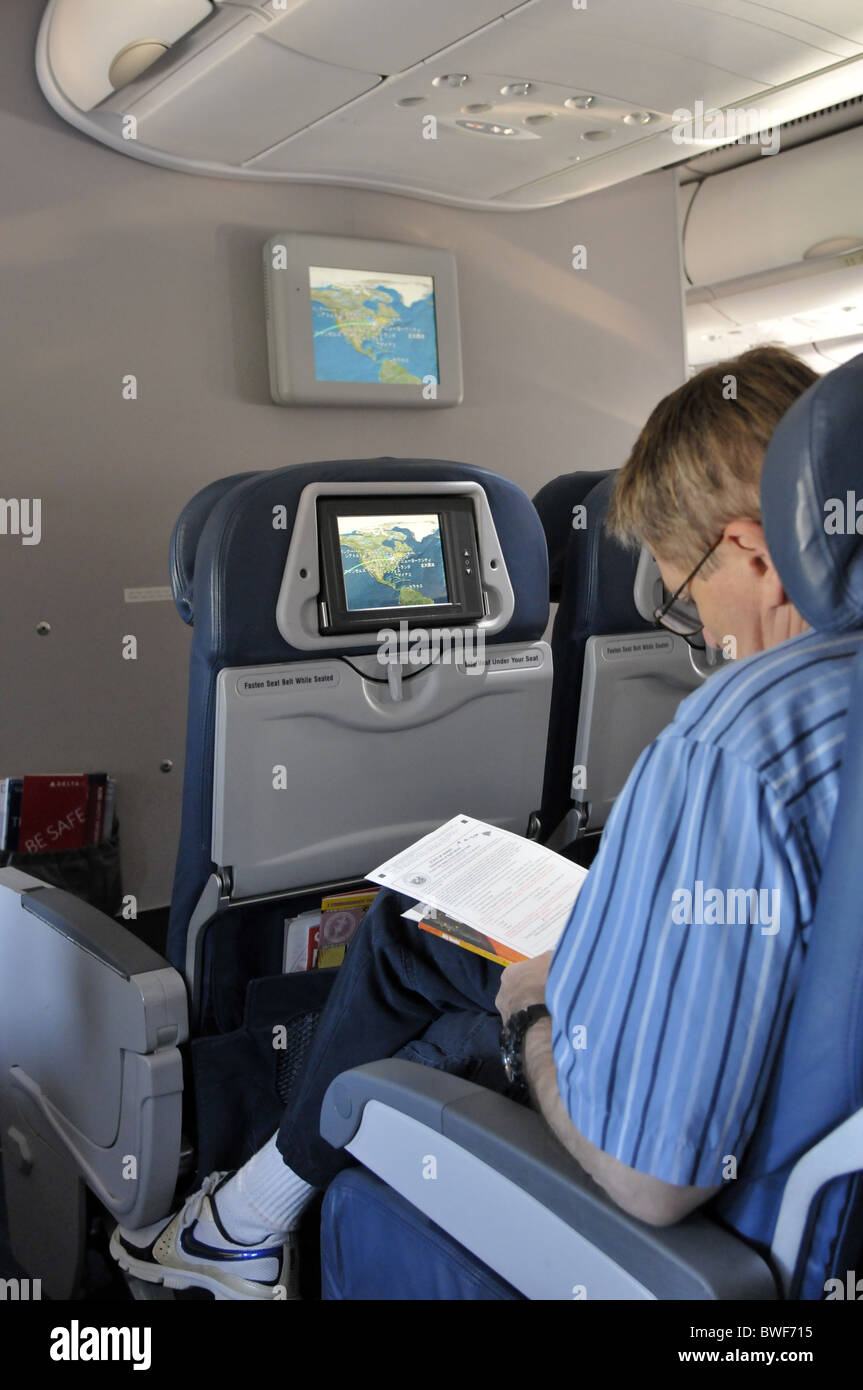 Passenger on commercial airplane reading map of destination on screen ...