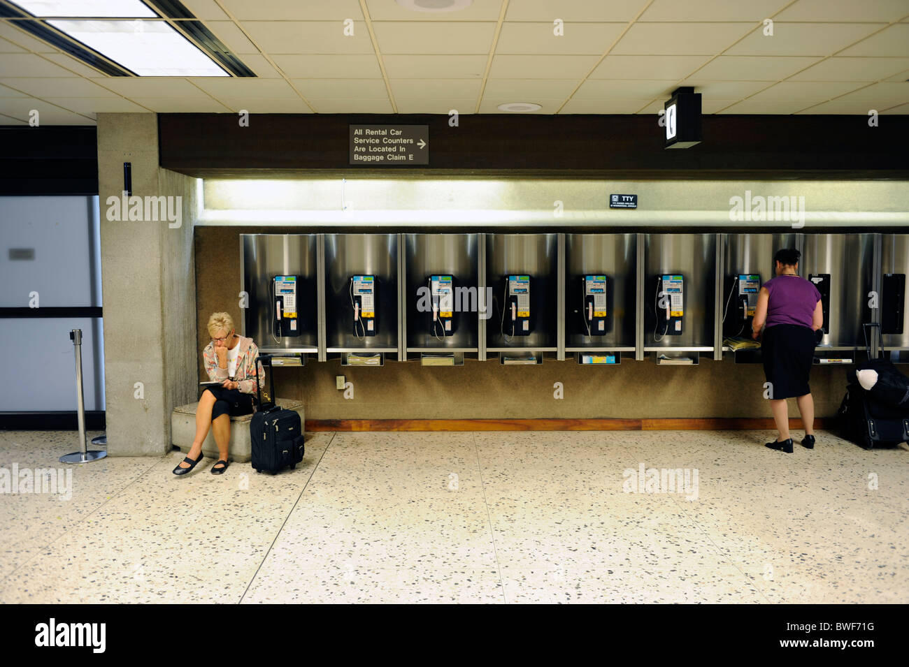 Travelers at bank of pay phones in airport terminal Stock Photo - Alamy