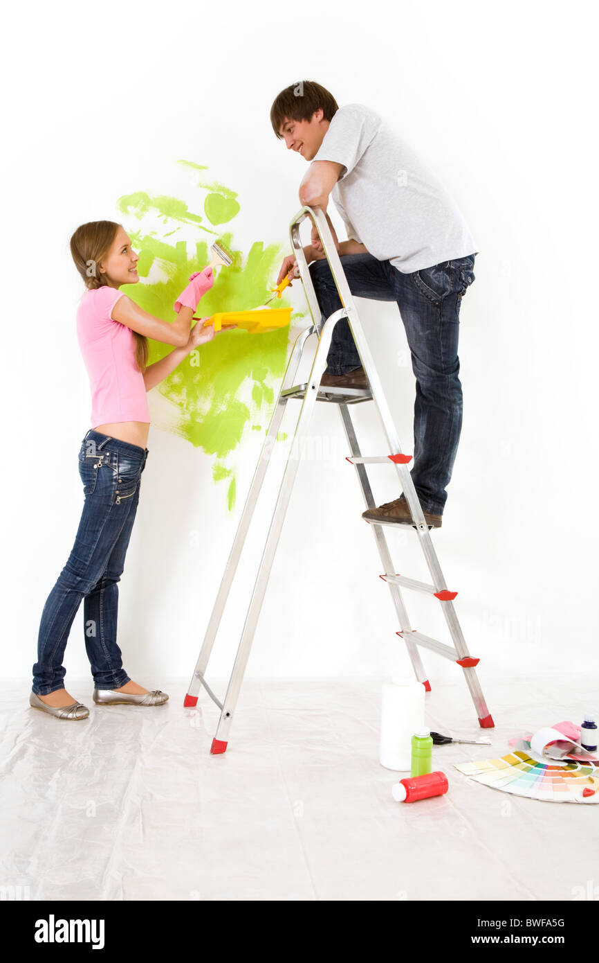 Affectionate couple helping each other to paint walls in new house ...