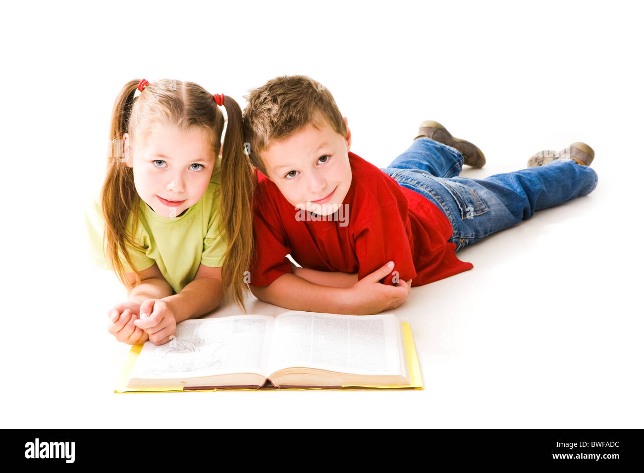 Smart schoolchildren looking at camera during reading book Stock Photo ...