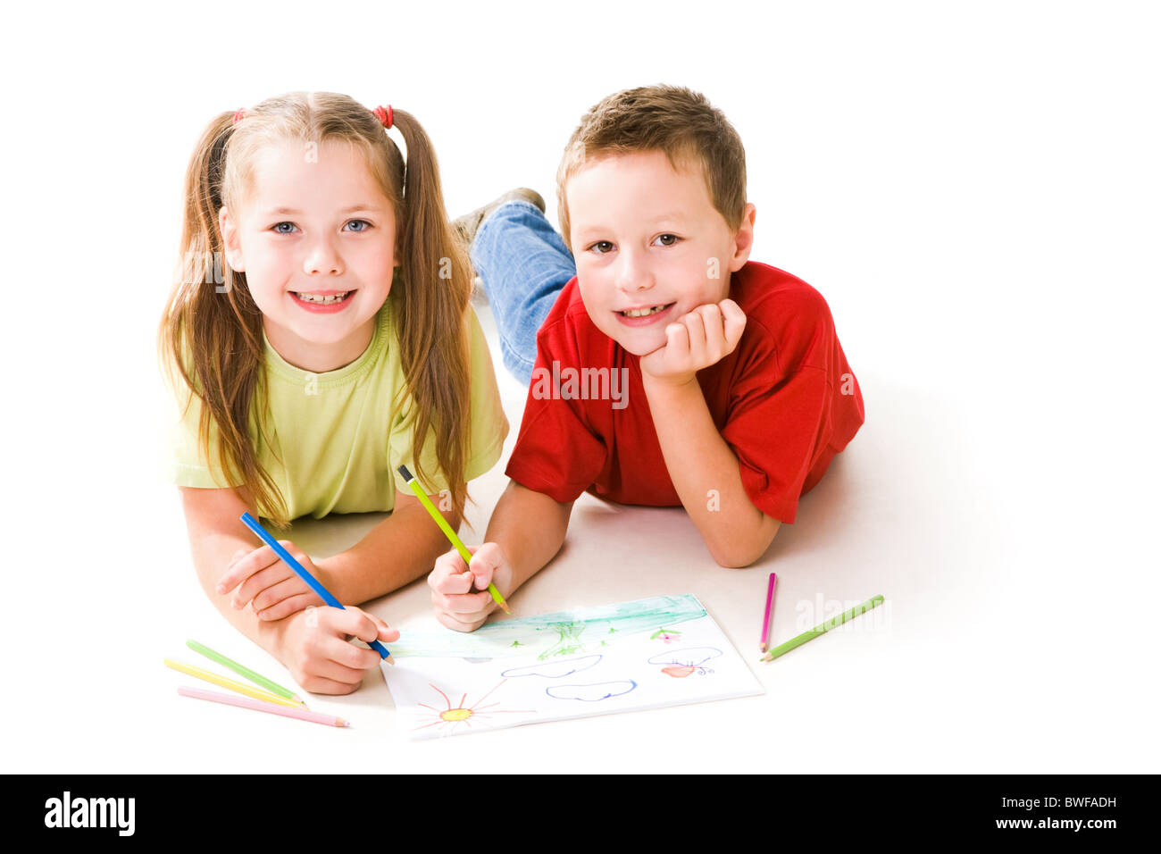 Smart schoolchildren looking at camera while drawing with colorful ...