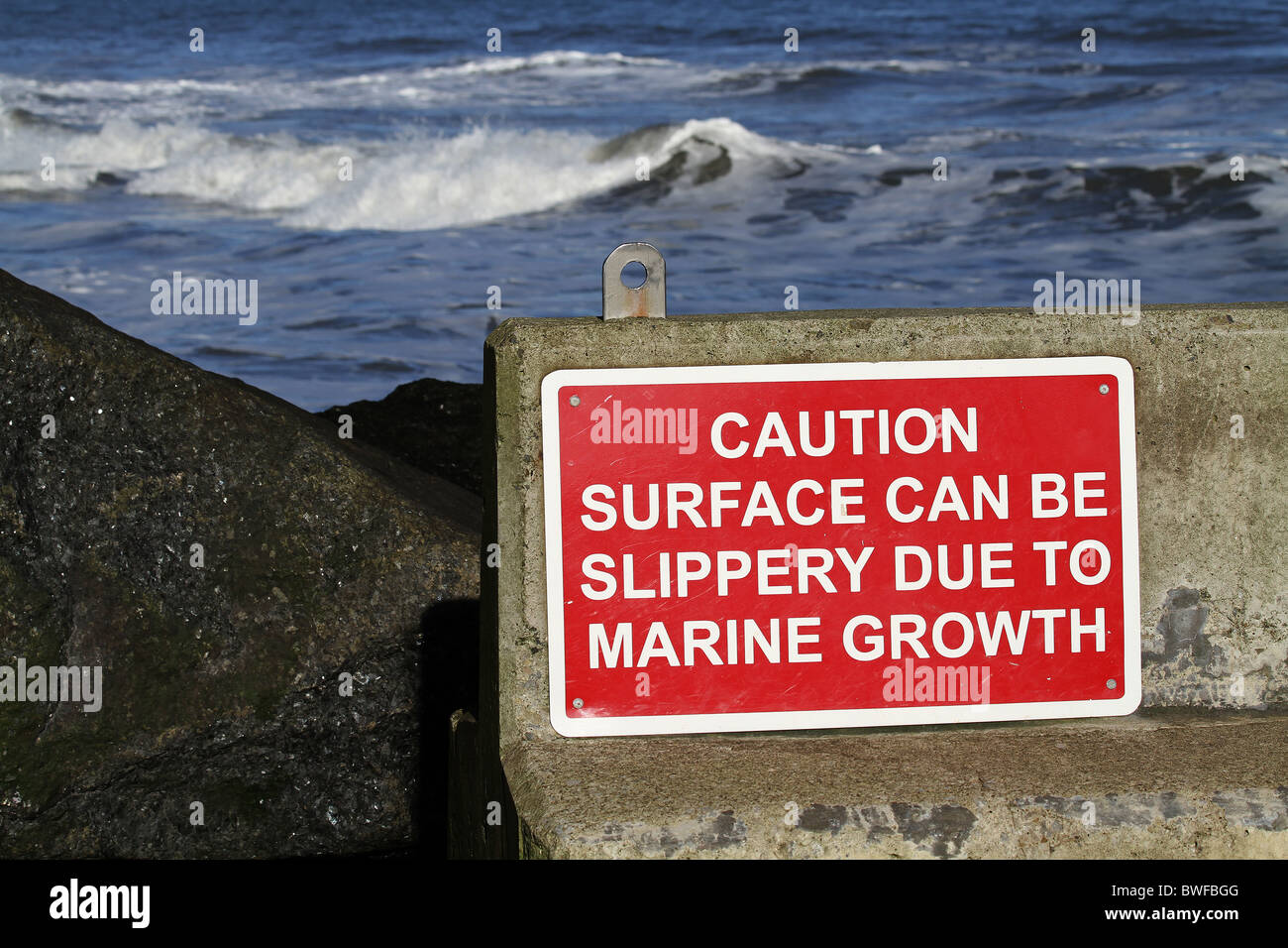 Rough sea and danger warning sign on jetty at Staithes in North ...