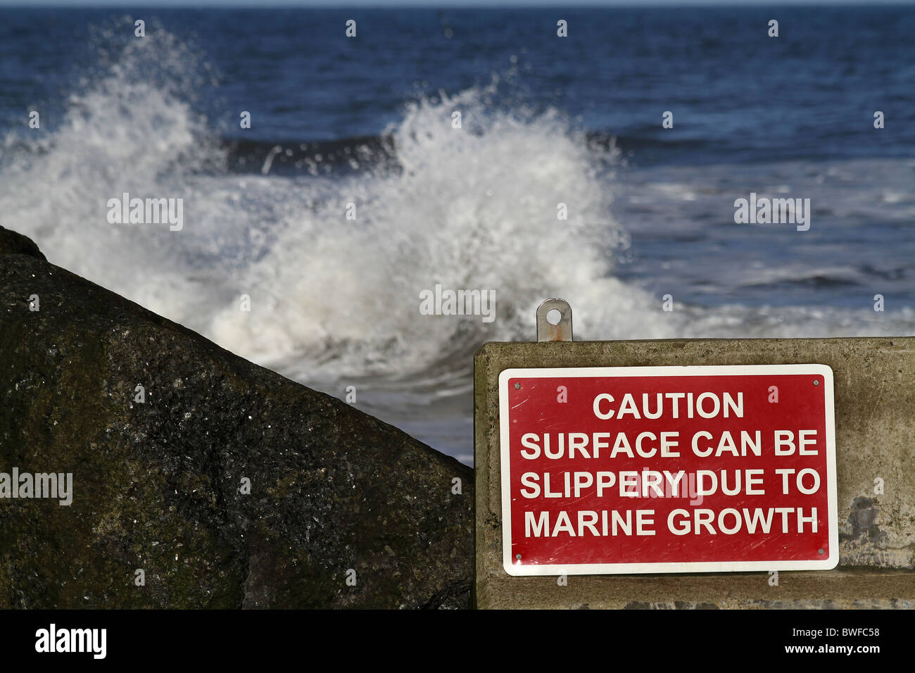 Rough sea and danger warning sign on jetty at Staithes in North ...