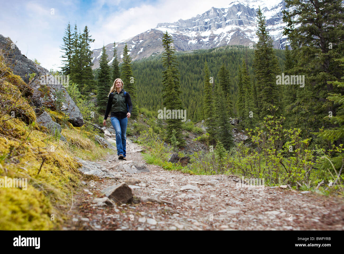 A happy woman walking on a path on a mountain hike in Banff National ...