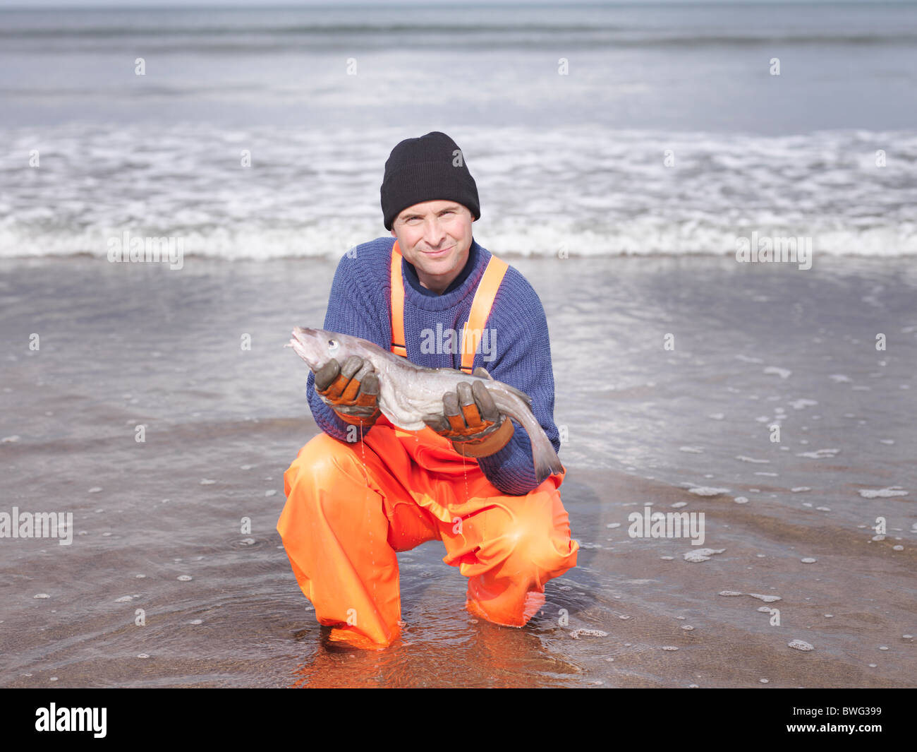 Fisherman on shore holding fish Stock Photo - Alamy