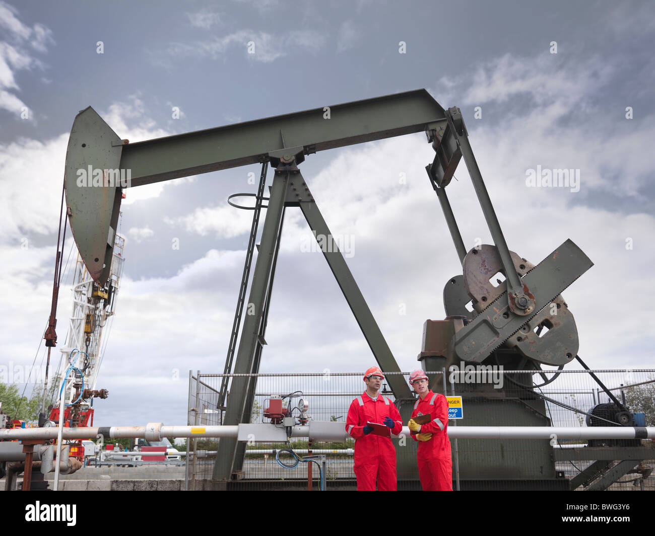 Workers in front of oil well pump Stock Photo - Alamy