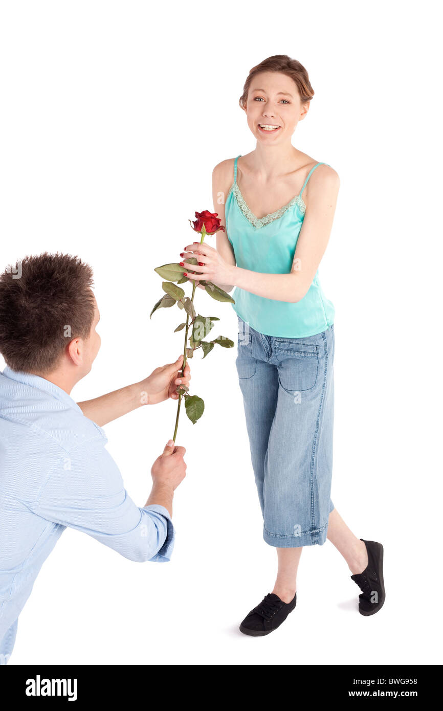 Man handing over a single red rose to a happy cheerful young woman ...