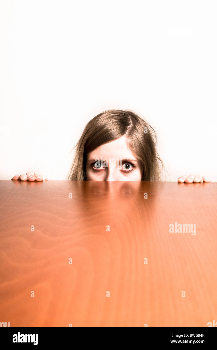 blond girl hiding behind a table, afraid or shy Stock Photo - Alamy