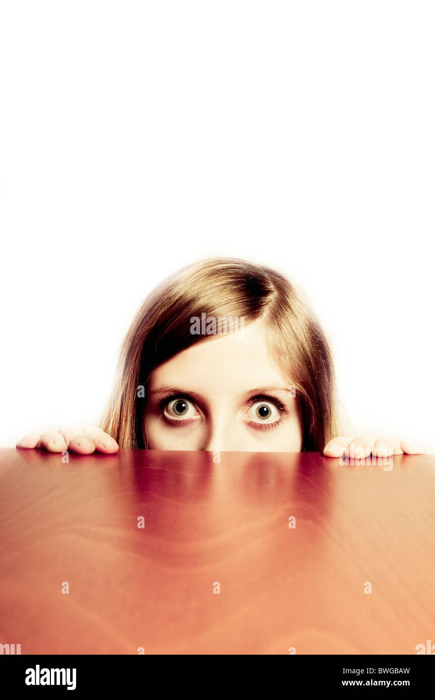 blond girl hiding behind a table, afraid or shy Stock Photo - Alamy