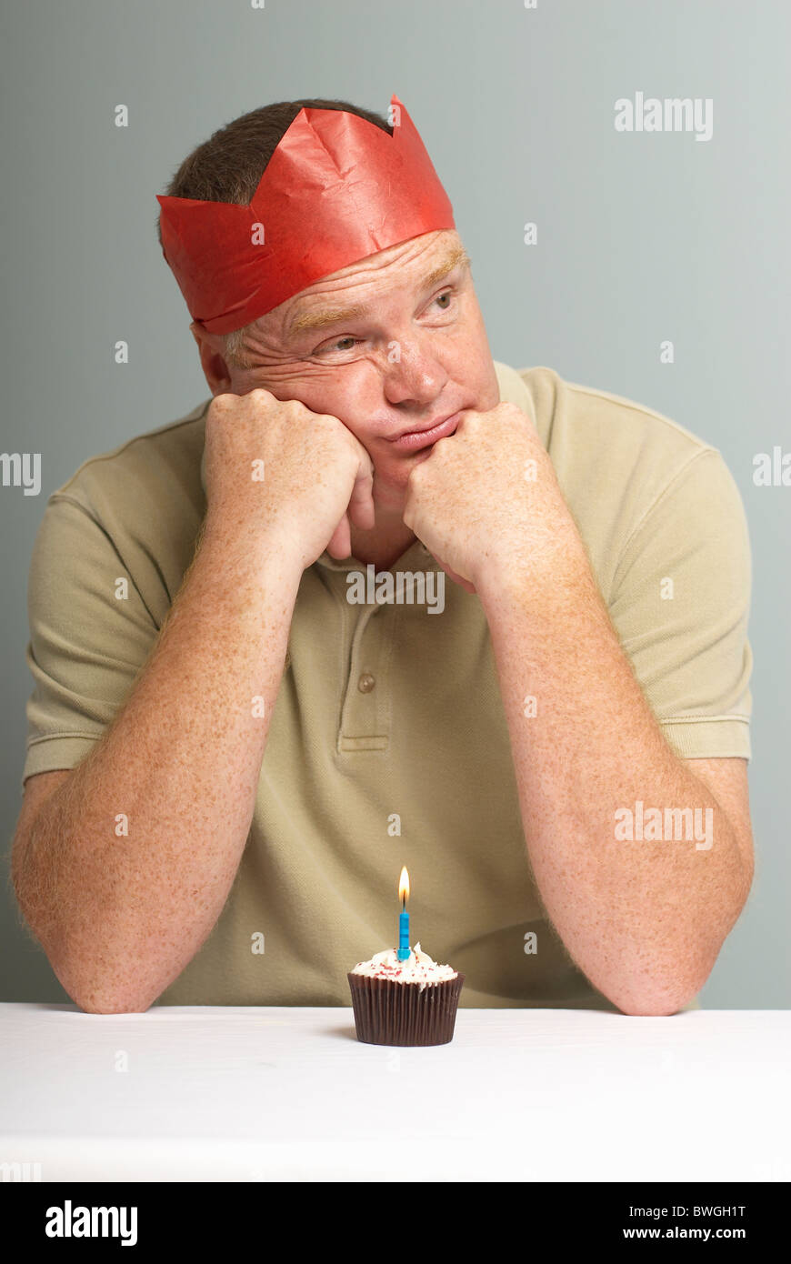 Man with small cake looking thoughtful Stock Photo - Alamy