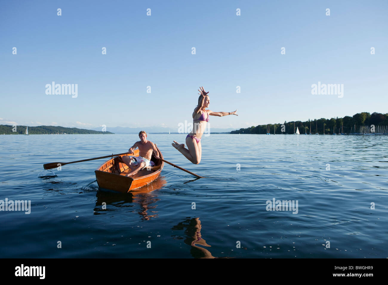 Young woman jumping off a row boat Stock Photo - Alamy