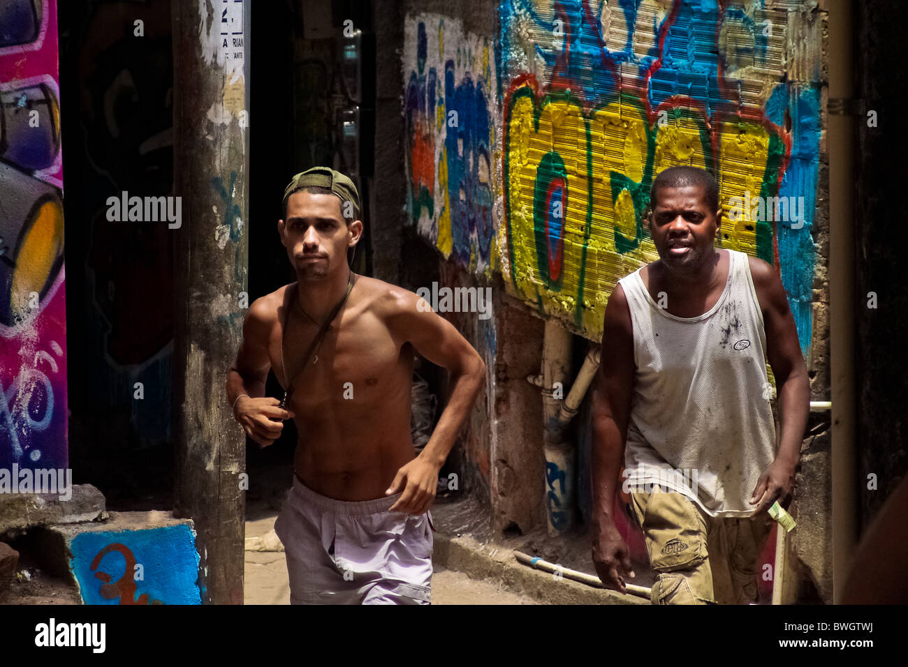 Brazilian men walk in front of the wall covered by graffiti in Rocinha ...