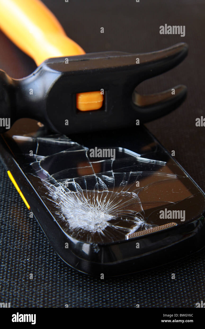 broken phone with a hammer on a black background Stock Photo - Alamy