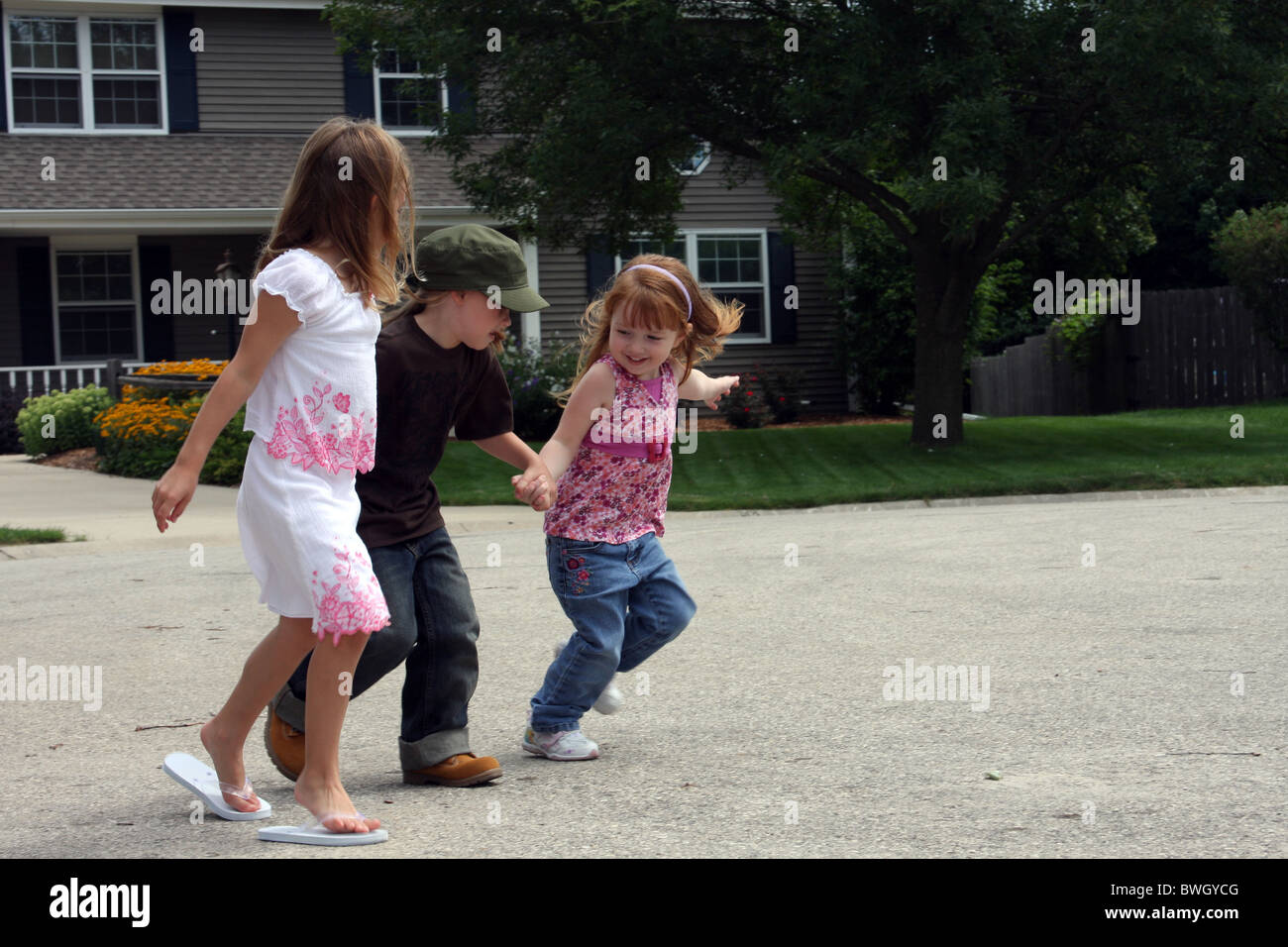 Three kids running in a suburban residential area Stock Photo - Alamy