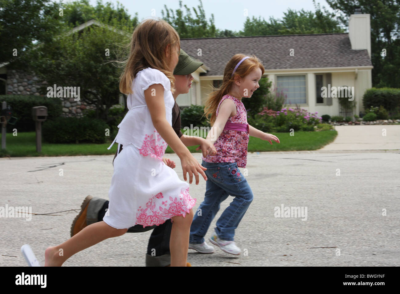 Three kids running in a suburban residential area Stock Photo - Alamy