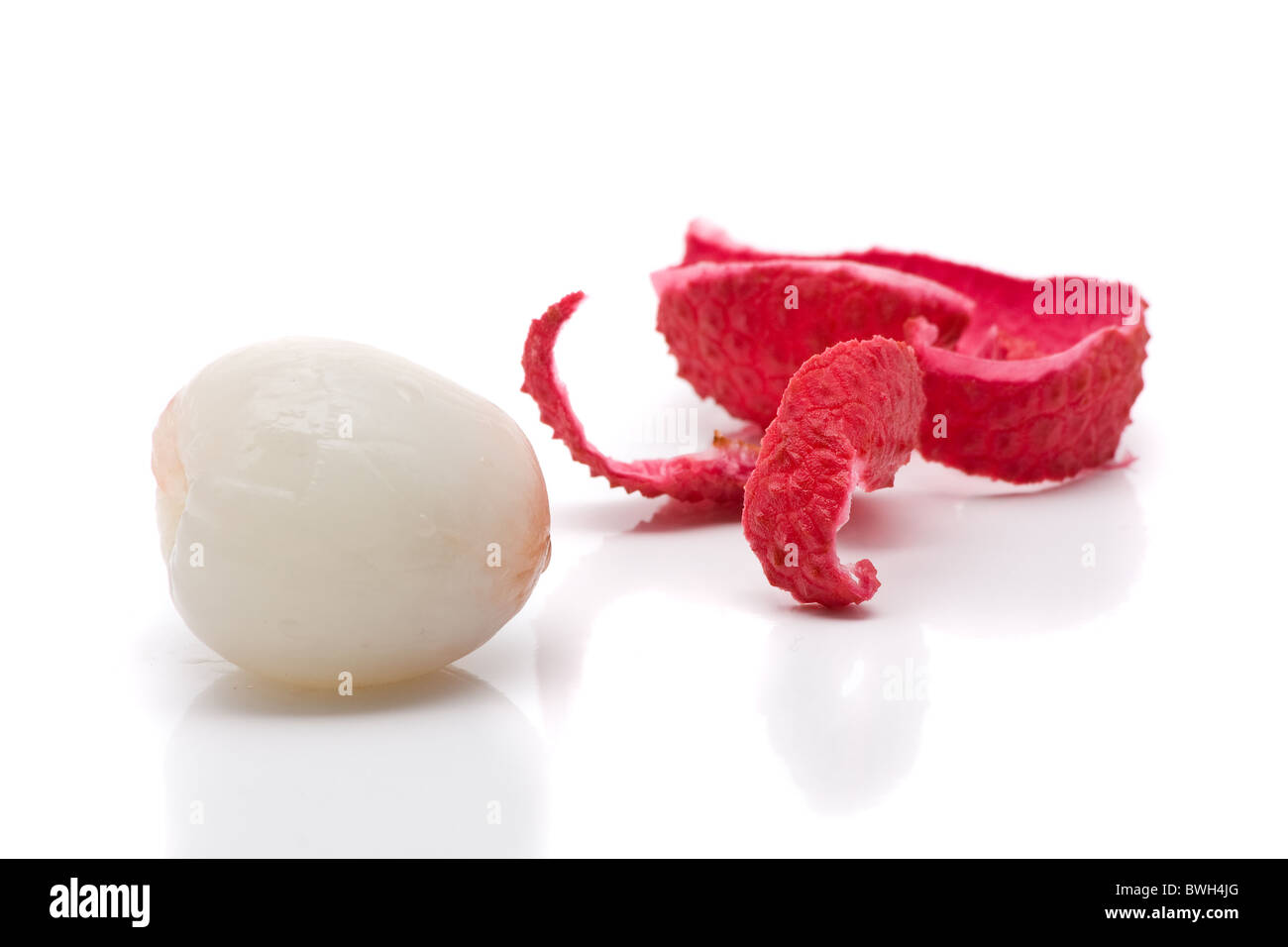 Peeled lychee with skin on reflective white bachround Stock Photo - Alamy