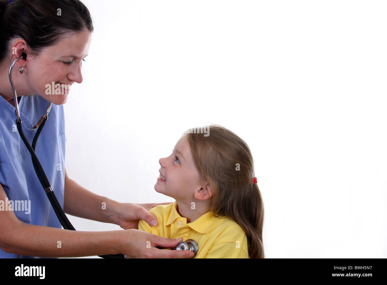 A young doctor using a stethoscope on a child to hear her heartbeat ...
