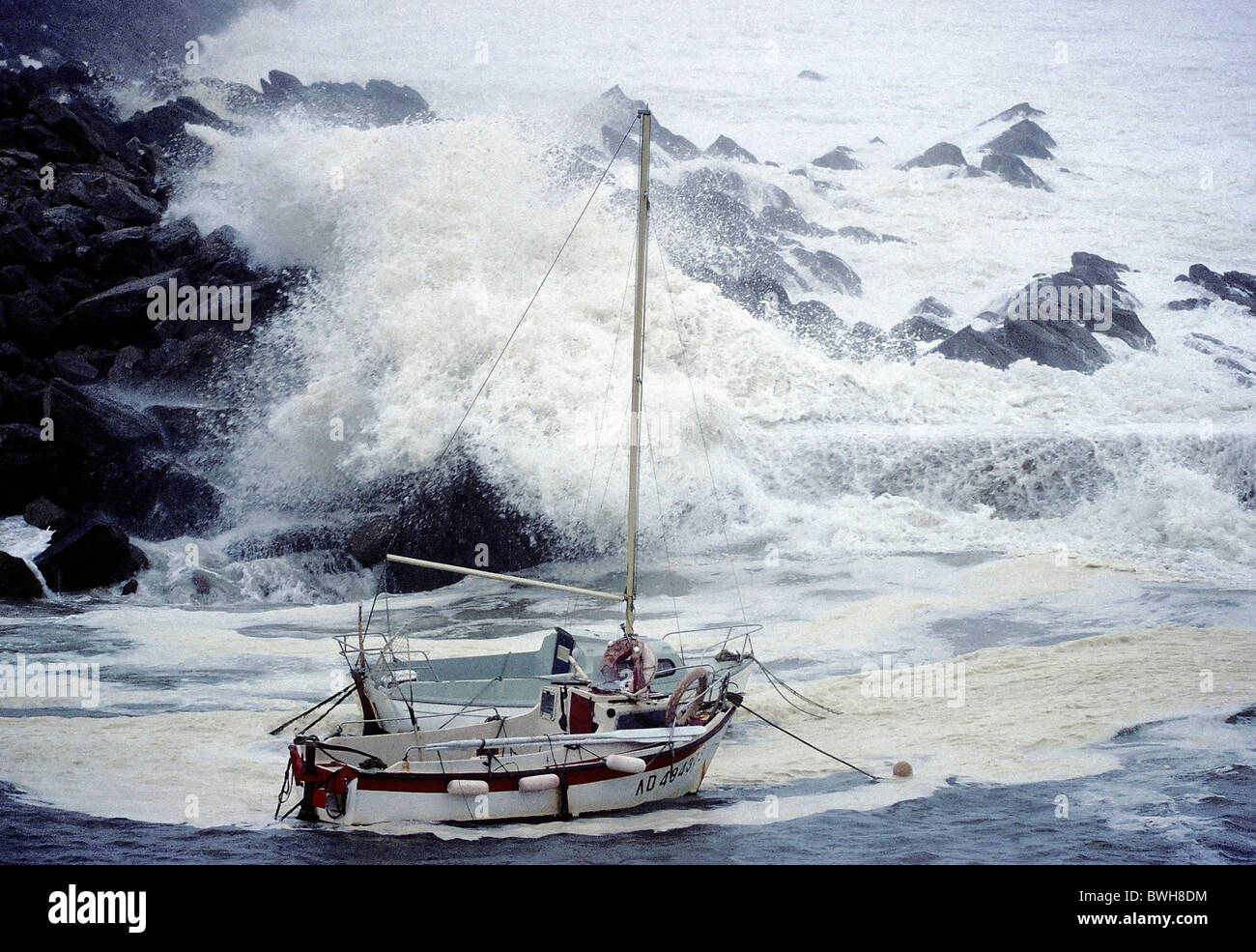High waves crashing over rocks, rocking small boats, stormy seas on the ...