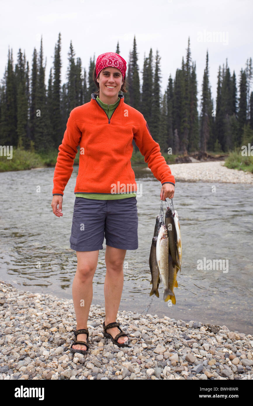 Young woman fishing, presenting her catch, Arctic grayling (Thymallus ...