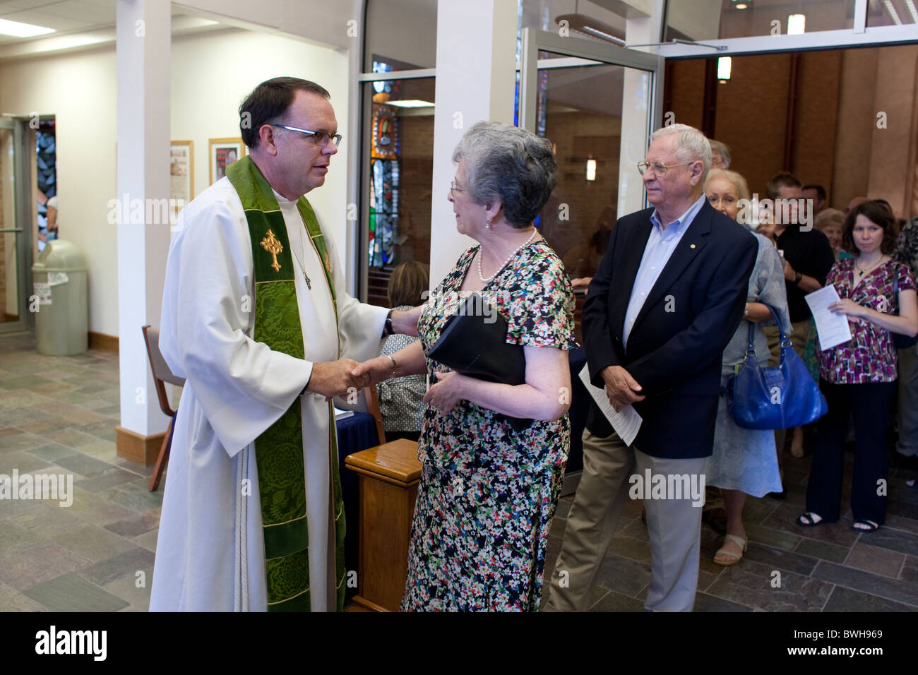 Anglo male pastor shakes hands as congregation lines up to leave the ...