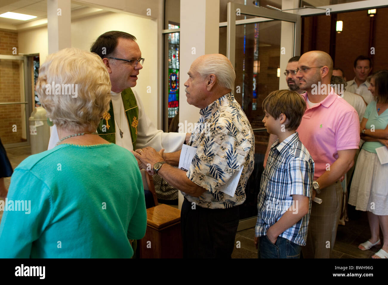 Anglo male pastor shakes hands as congregation lines up to leave the ...