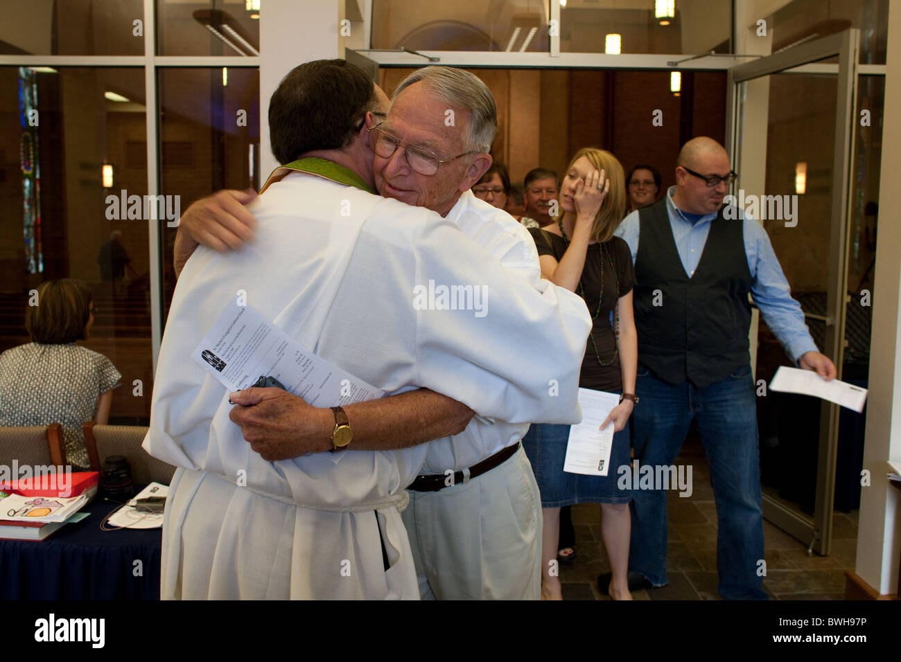 Anglo male congregation member greets pastor with a hug as he leaves ...
