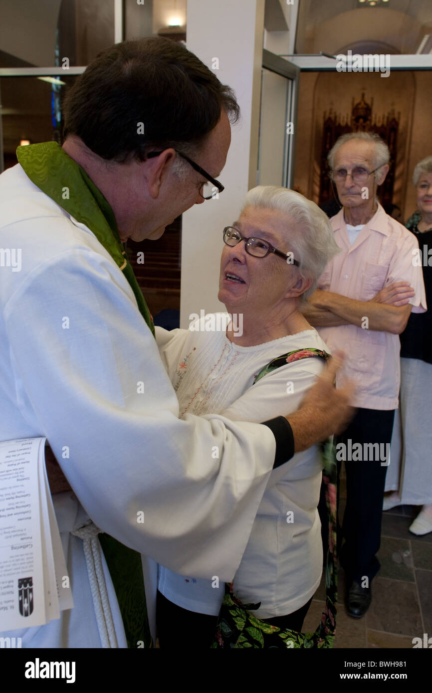 Elderly female congregation member greets pastor with a hug as she ...