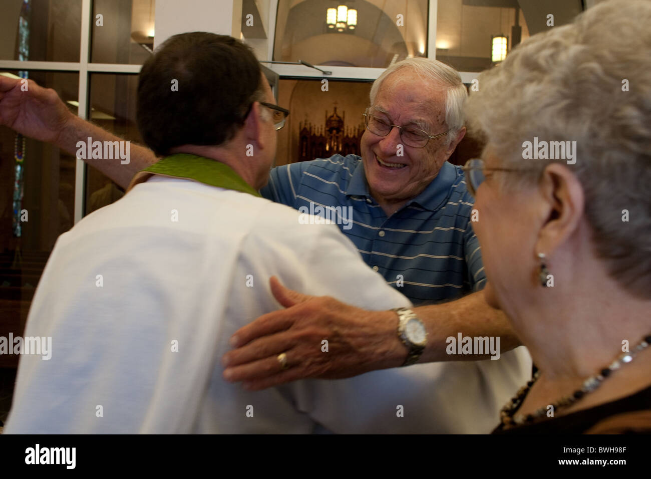 Anglo male congregation member greets pastor with a hug as he leaves ...