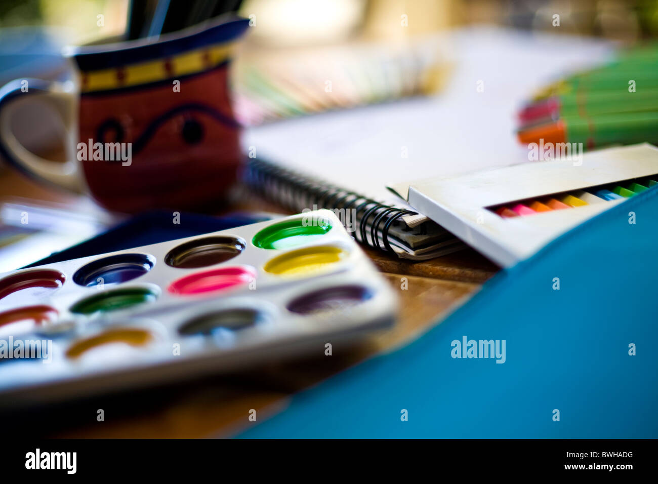 Assorted stationary - paper paints pencils and crayons laid about on ...