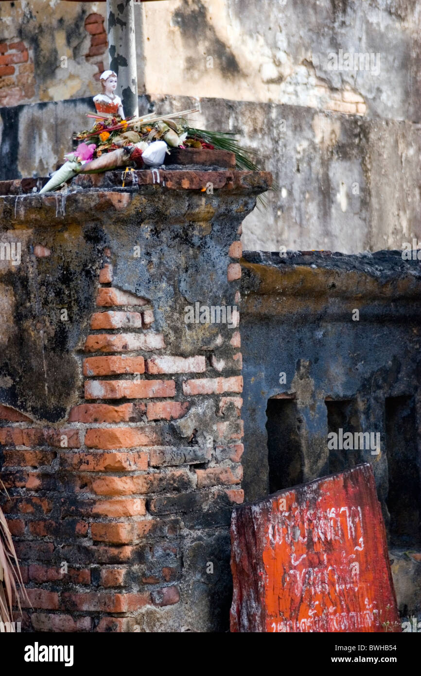 A broken Buddhist statue is on a brick wall at a temple in Nan ...