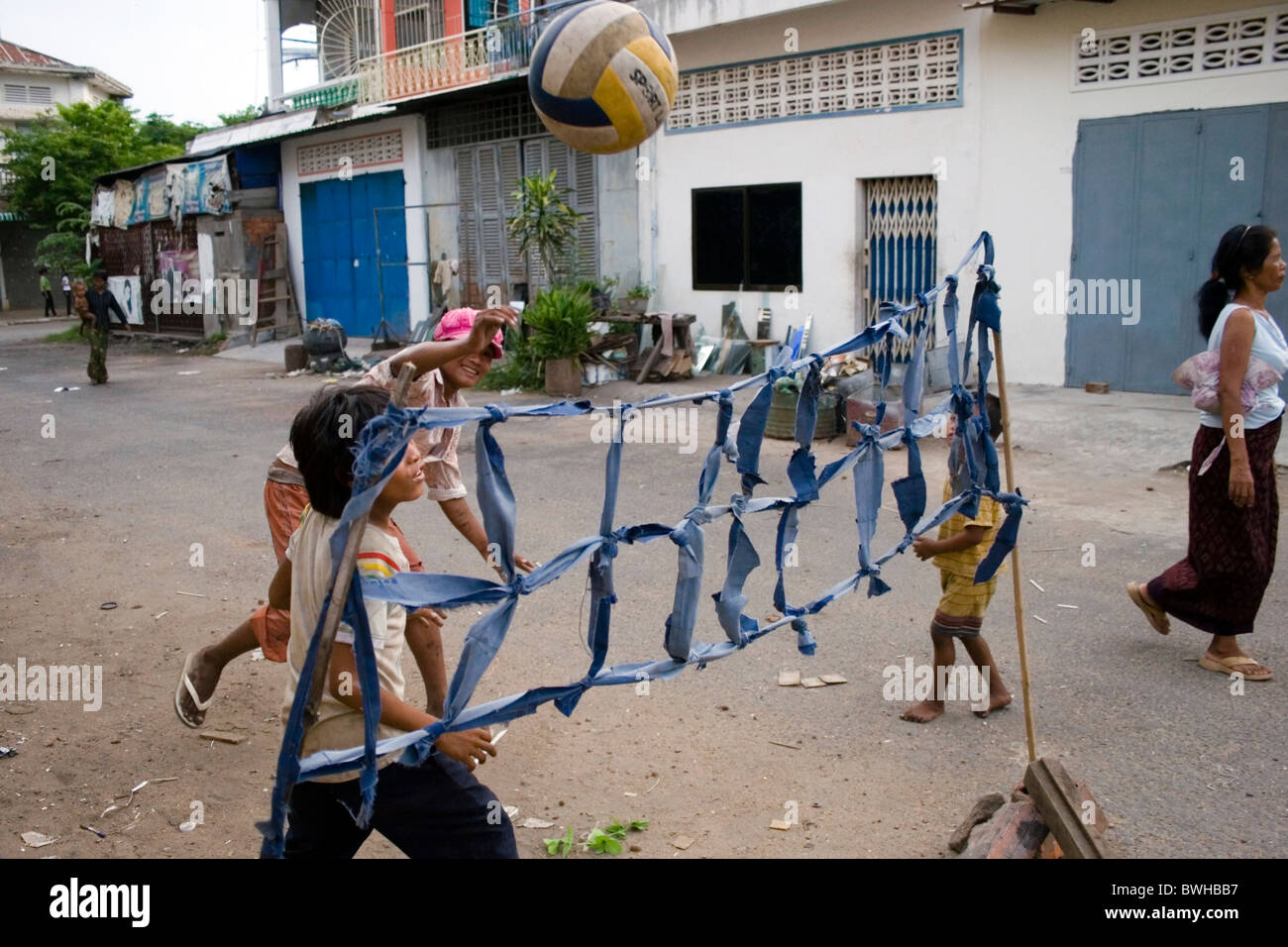 Boys are playing volleyball with a net made of rags on a street in ...