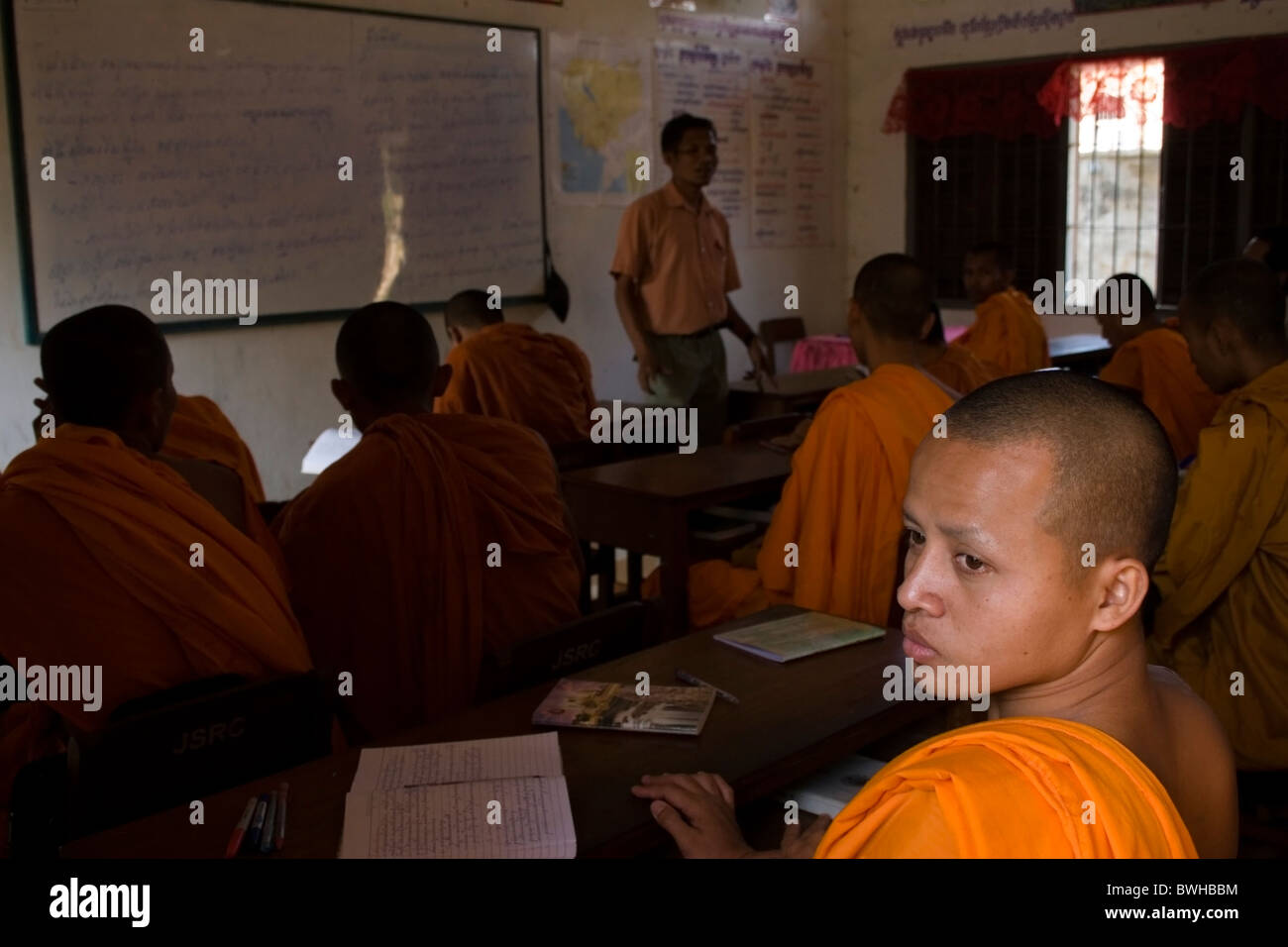 A Buddhist monk is looking out a classroom window during a high school ...