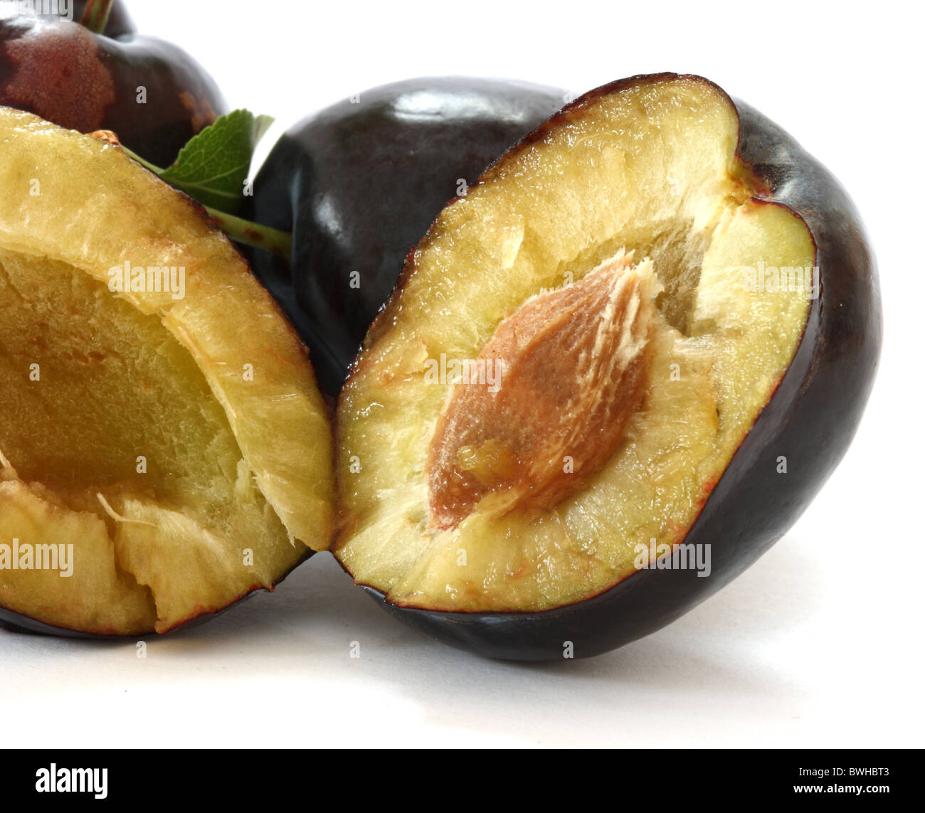 Three fresh plums on white background - one opened Stock Photo - Alamy